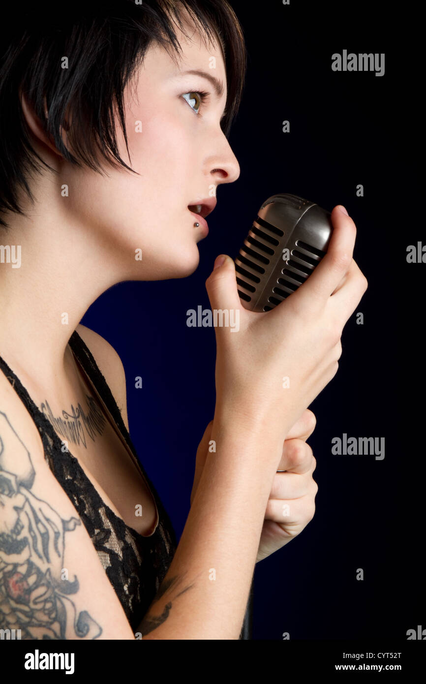 Pretty girl singing into microphone Stock Photo - Alamy