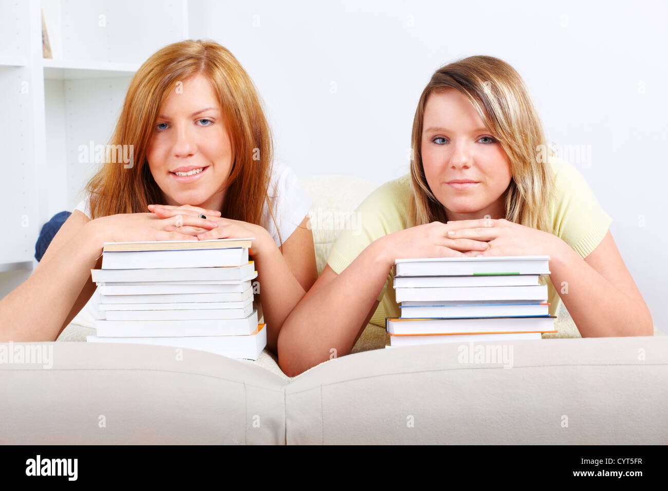 Two cute girls with piles of books Stock Photo - Alamy