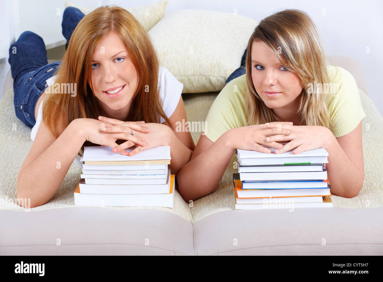 Two cute girls with piles of books Stock Photo - Alamy