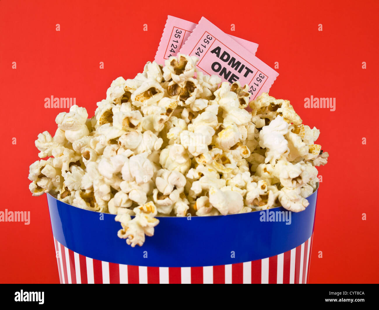 A popcorn bucket over a red background. Movie stubs sitting over the ...