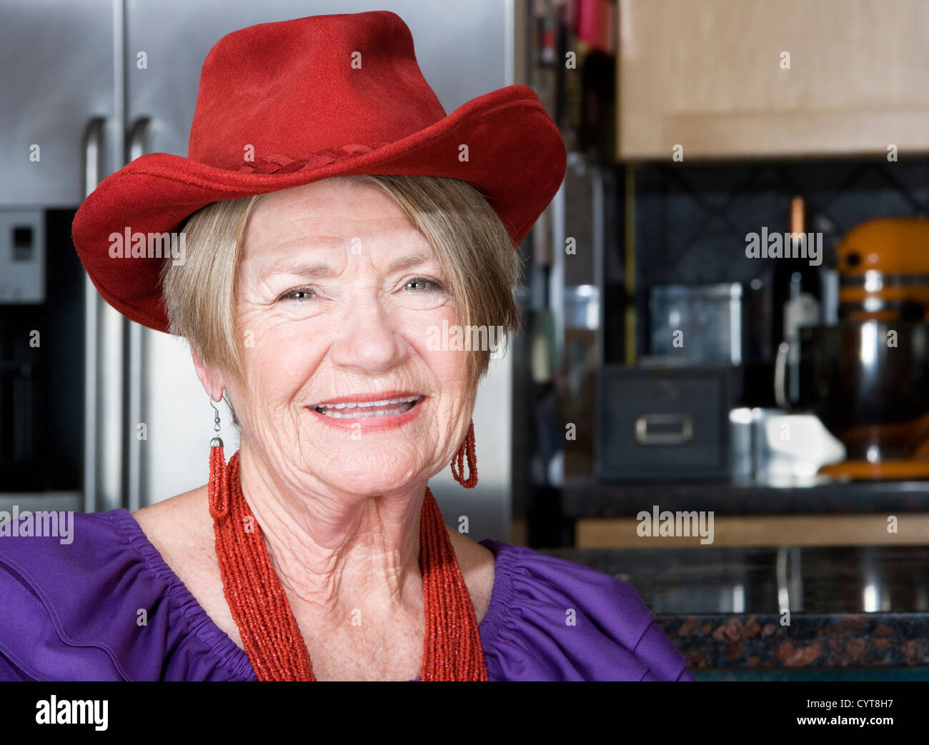 Friendly senior woman wearing a red cowboy hat Stock Photo - Alamy