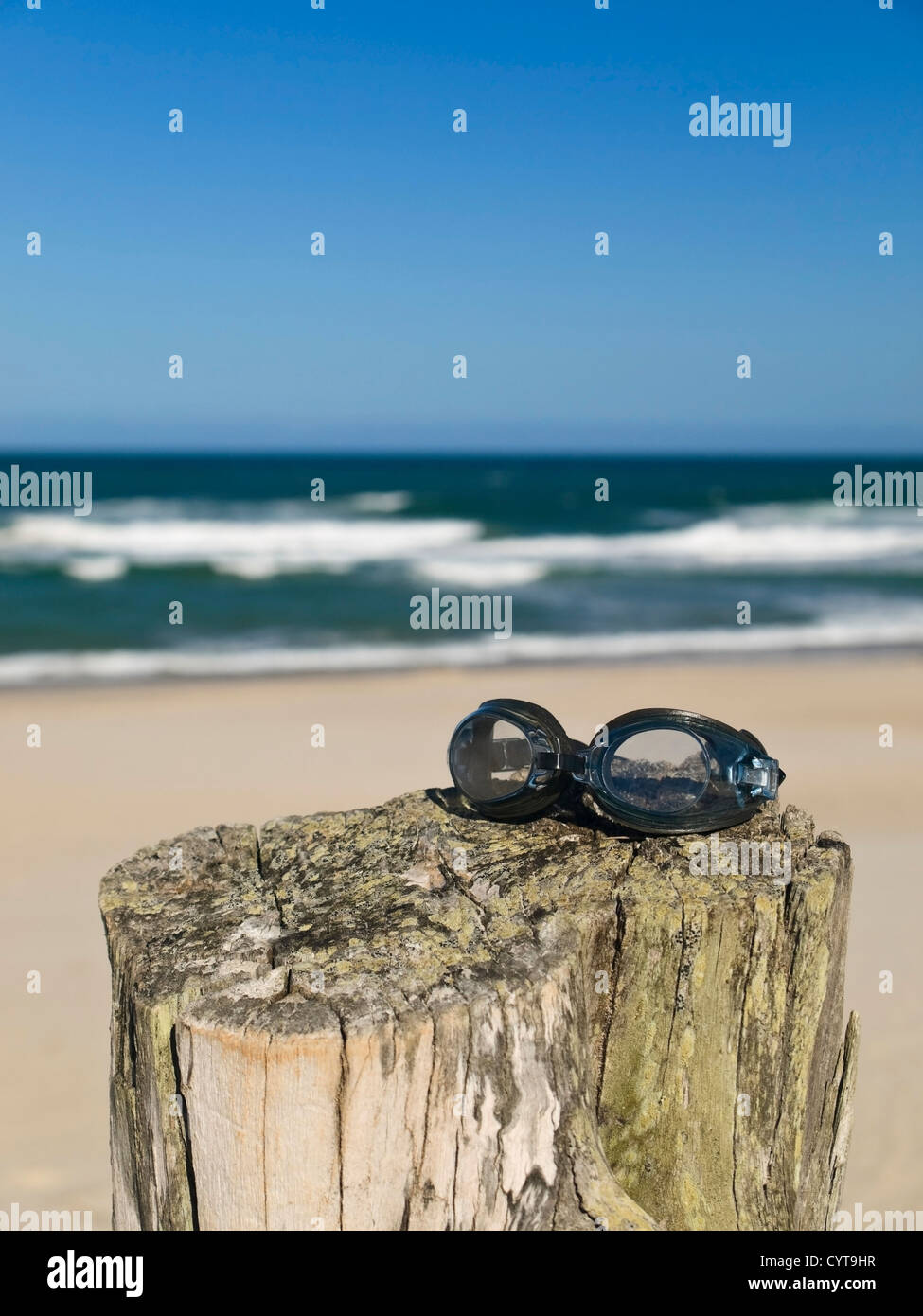A pair of goggles sitting over a log in the beach Stock Photo - Alamy