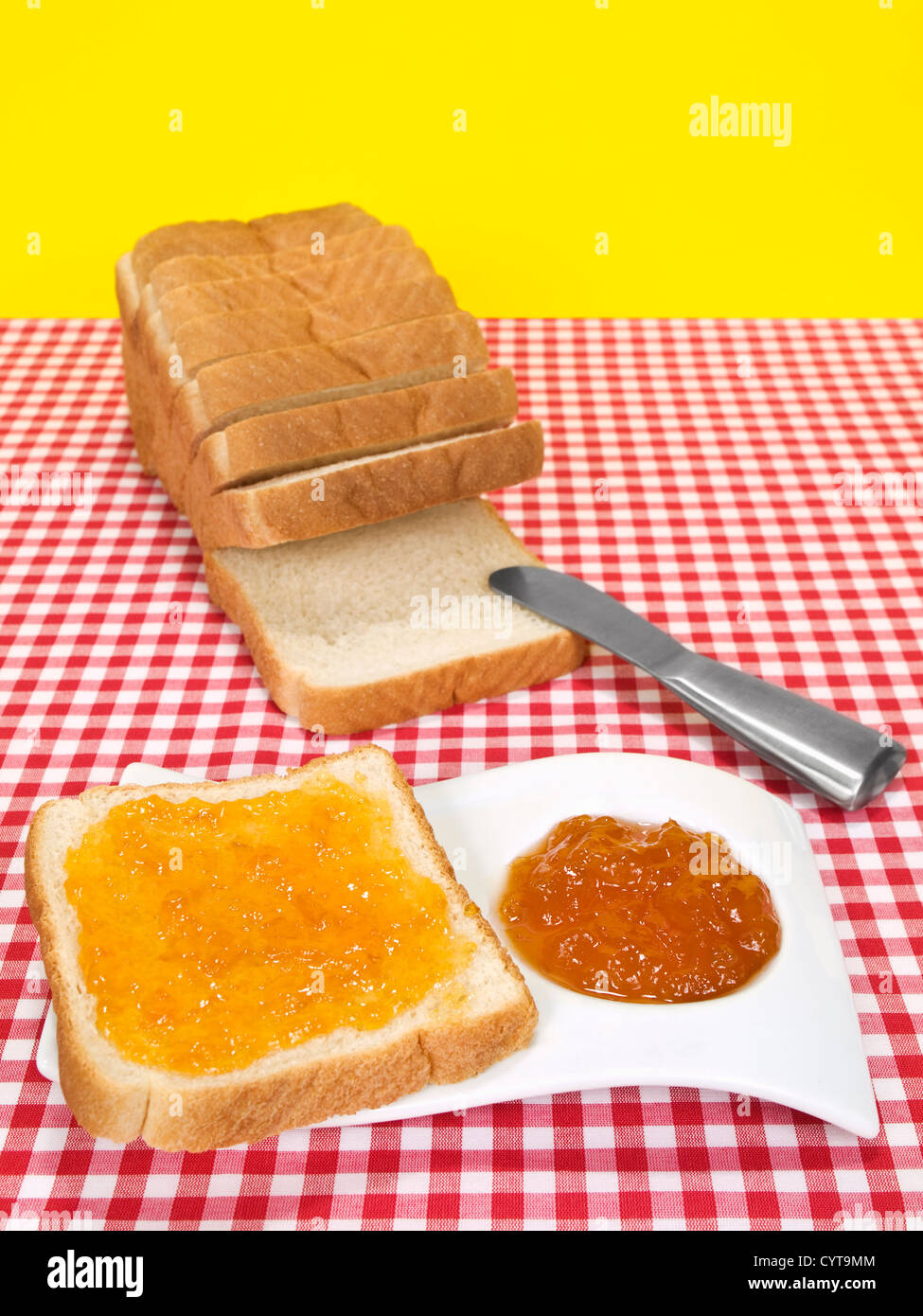 A slice of bread spread with jam beside a loaf of sliced bread Stock ...