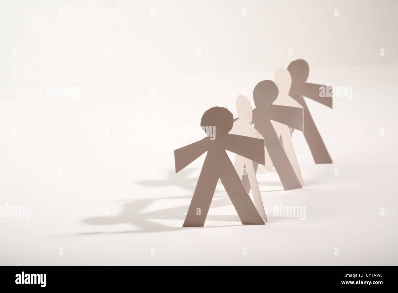 Line of cutout paper dolls throwing a shadow Stock Photo - Alamy