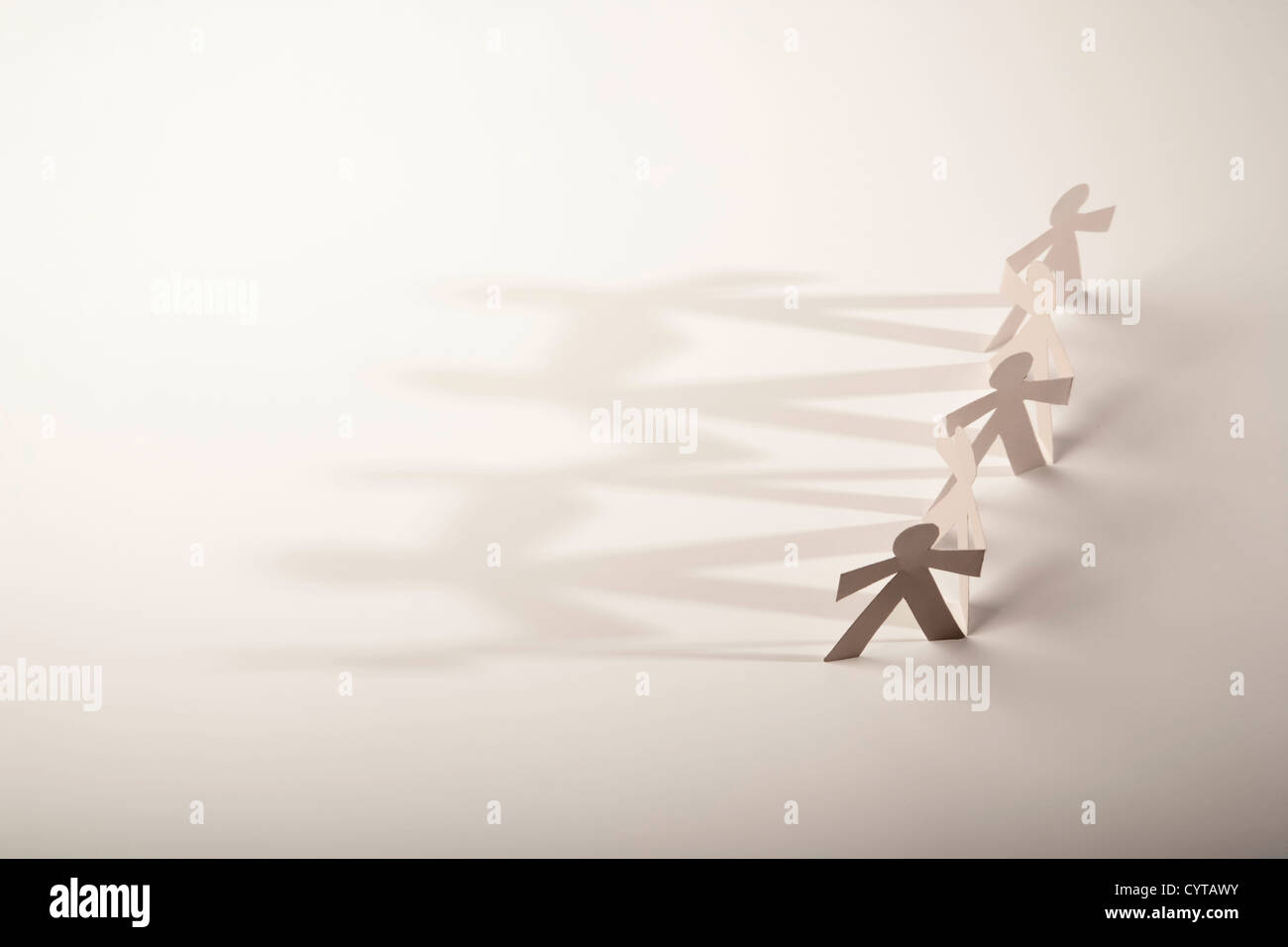 Line of cutout paper dolls throwing a shadow Stock Photo - Alamy