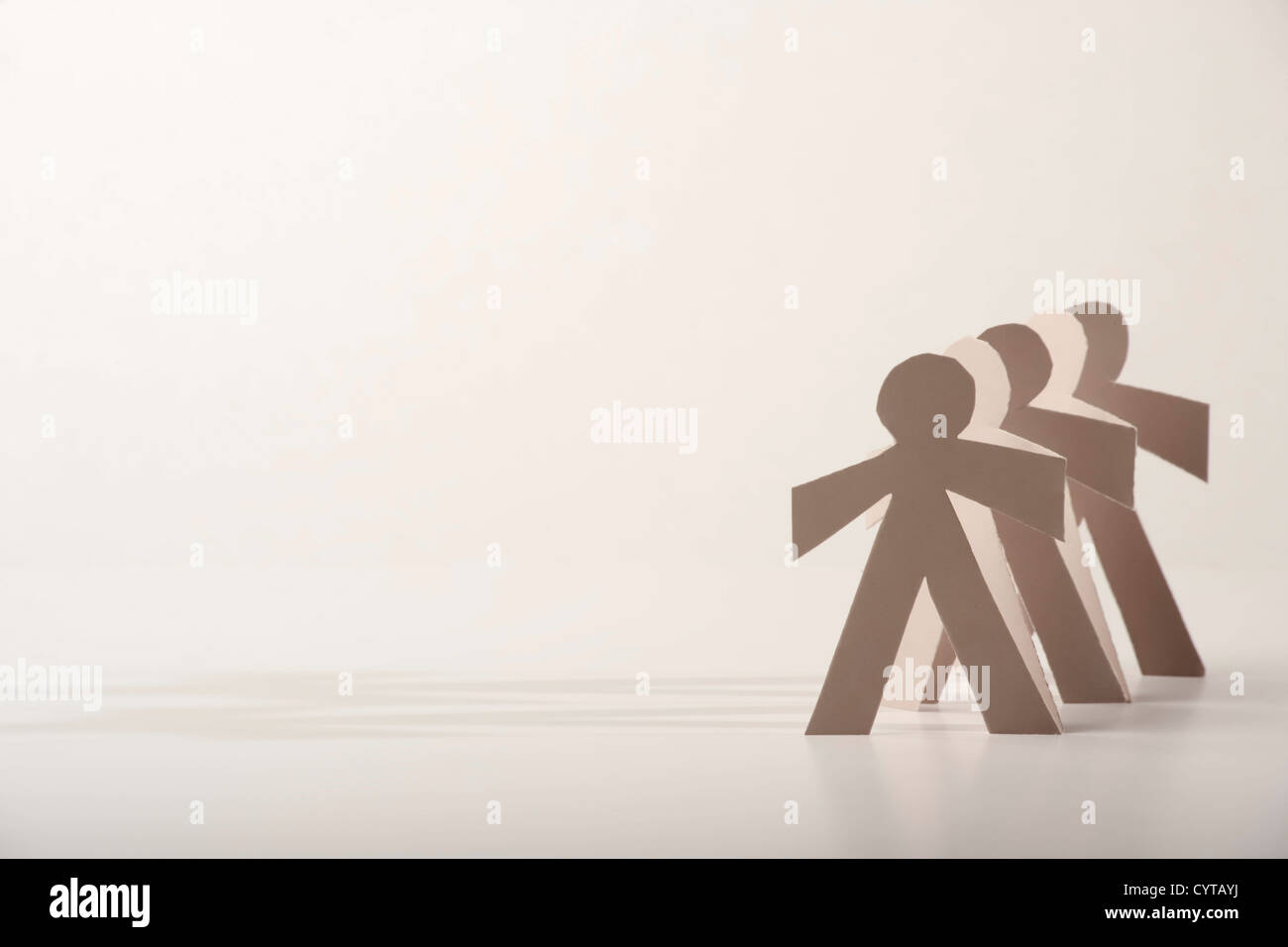 Line of cutout paper dolls throwing a shadow Stock Photo - Alamy