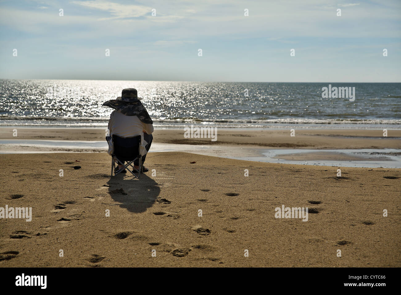 Senior man sitting at beach watching sunset Stock Photo - Alamy
