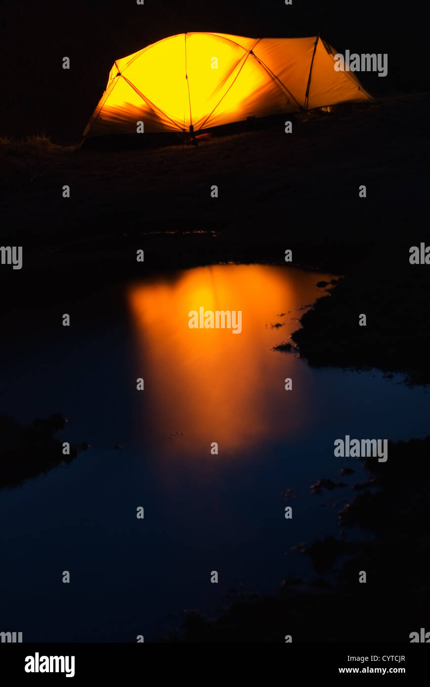Tent in the night with weak light and small lake Stock Photo - Alamy