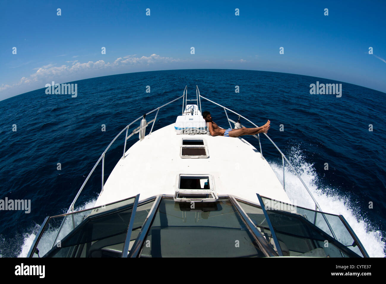 yacht boat heading to horizon wide angle view with men enjoying sun at ...