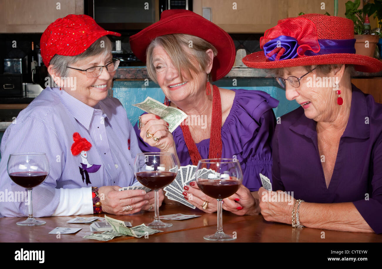 Ladies wearing red hats playing a hand of cards Stock Photo - Alamy