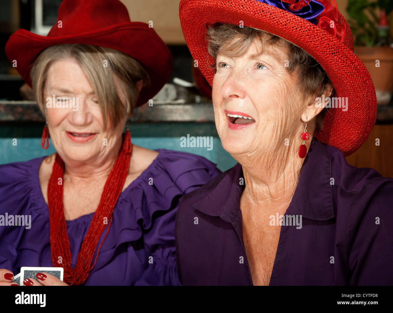 Ladies wearing red hats playing a hand of cards Stock Photo - Alamy