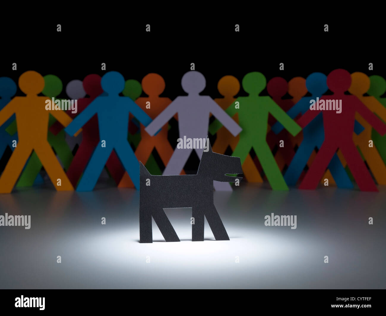 A black paper dog stands under the spotlight in front of a multicolor ...