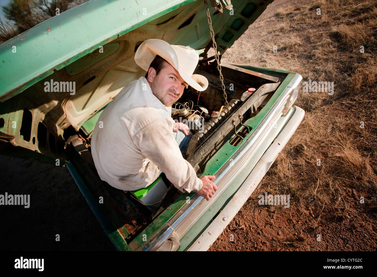 Man in cowboy hat under the hood of truck Stock Photo - Alamy