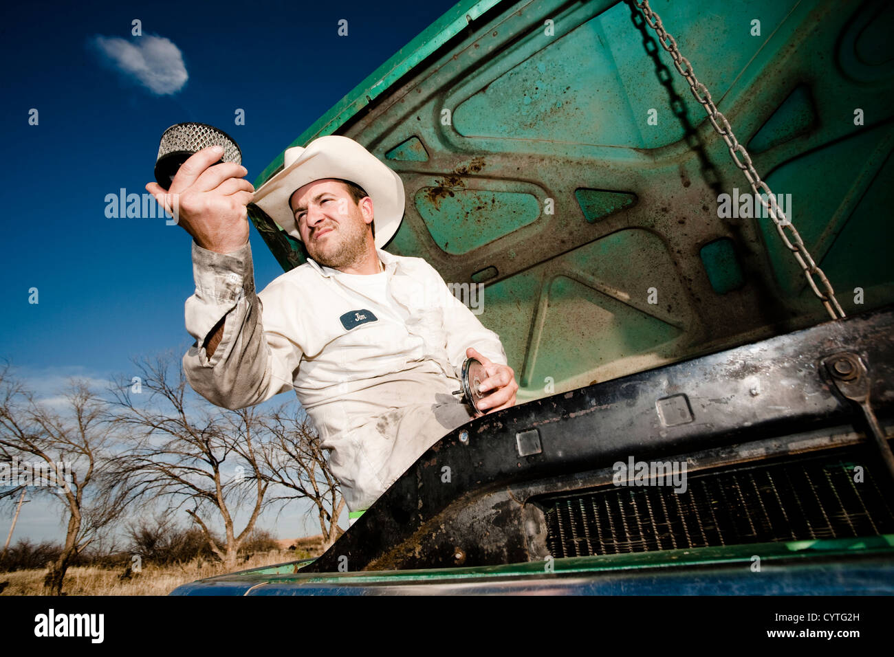 Man in cowboy hat under the hood of truck Stock Photo - Alamy