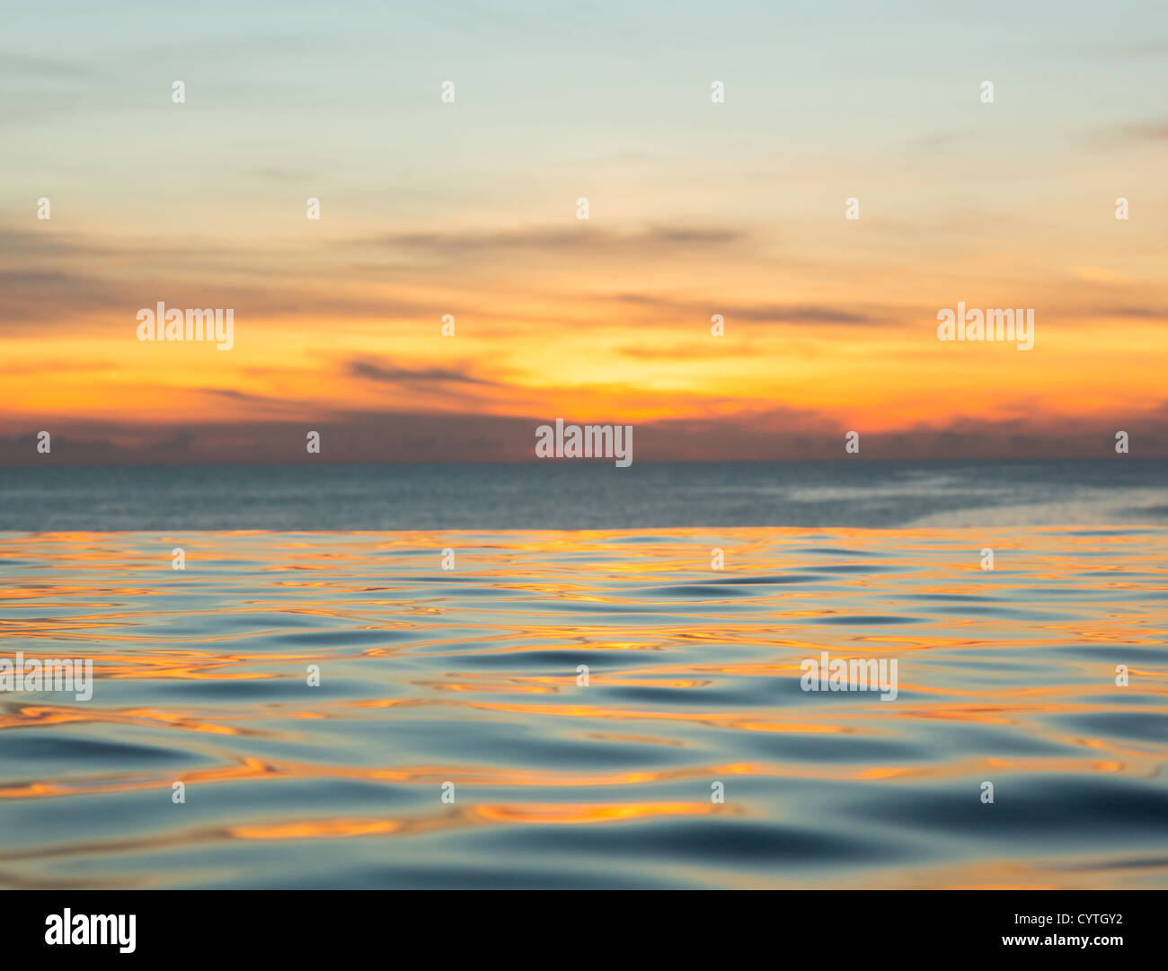 Edge of infinity swimming pool overlooking ocean at sunset Stock Photo ...