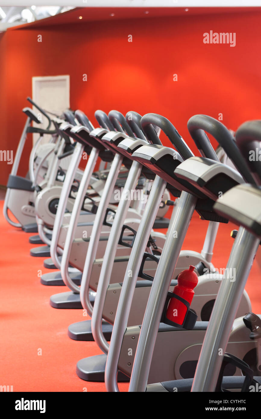 Bicycles in a row in a gym with red background and floor Stock Photo ...