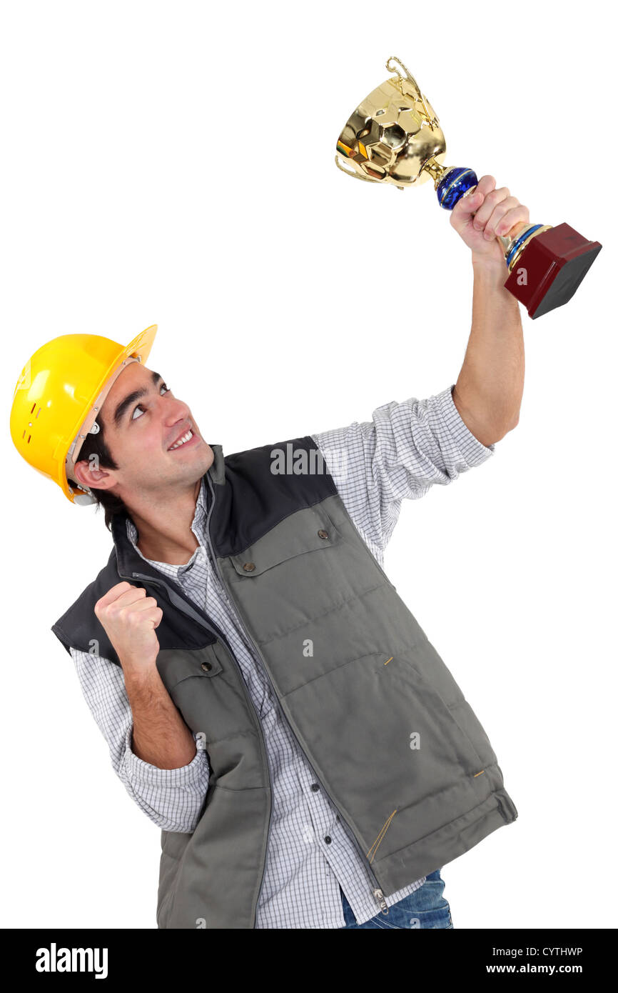 A construction worker holding a trophy Stock Photo - Alamy