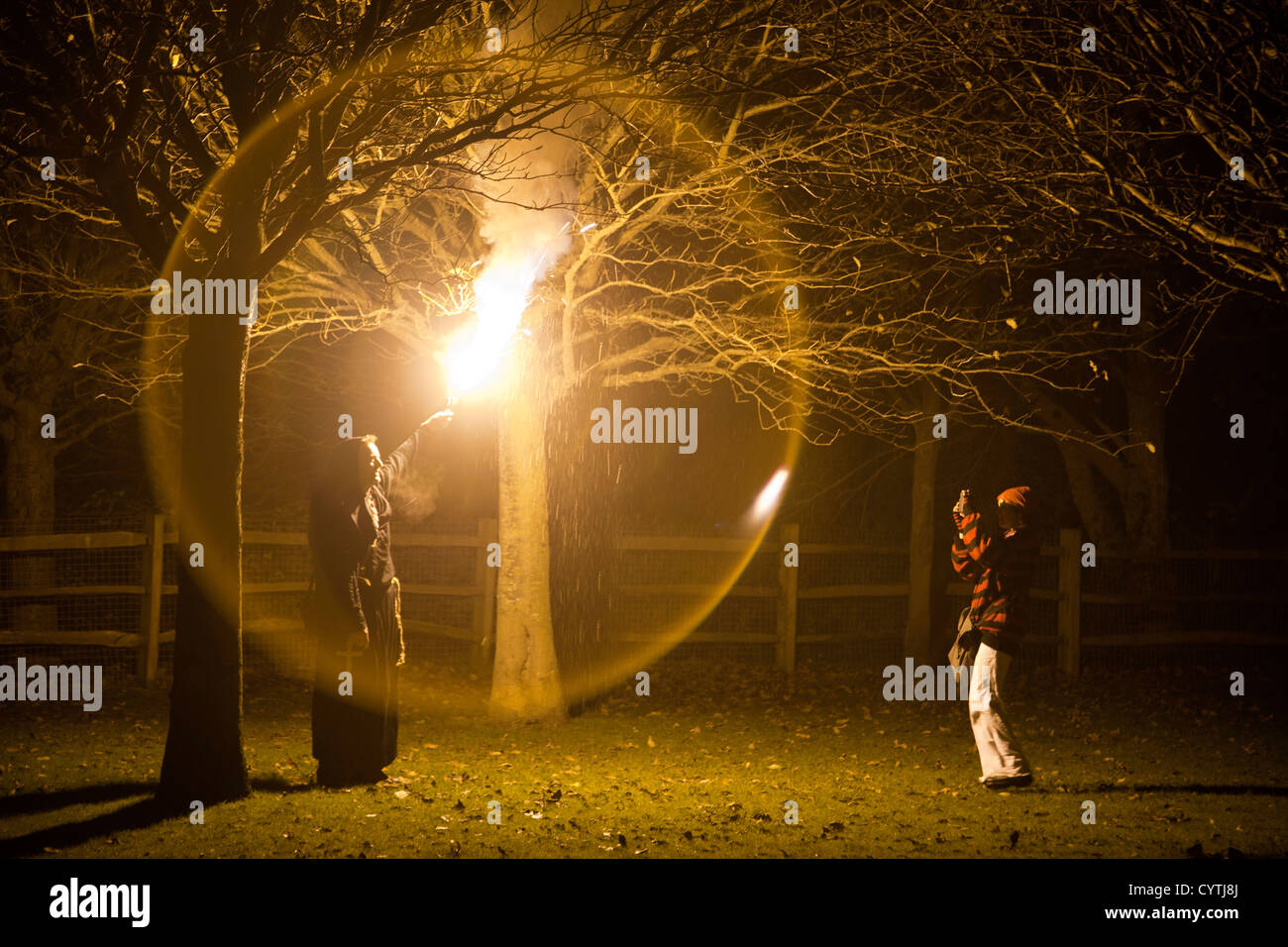 A monk holding a flaming torch creating a halo whilst a man films him ...
