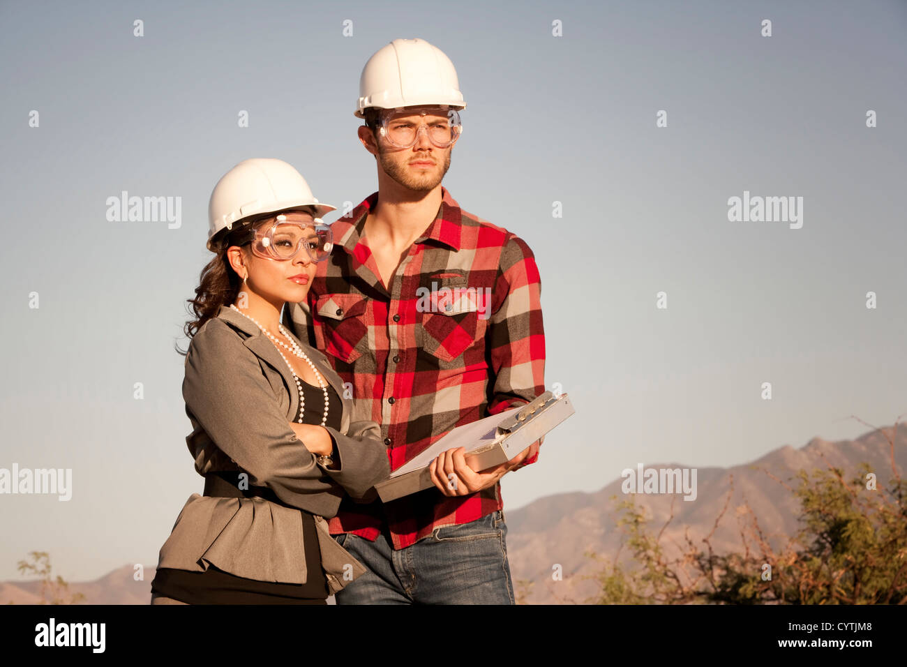 Handsome man and pretty woman outdoors wearing protective hardhats ...