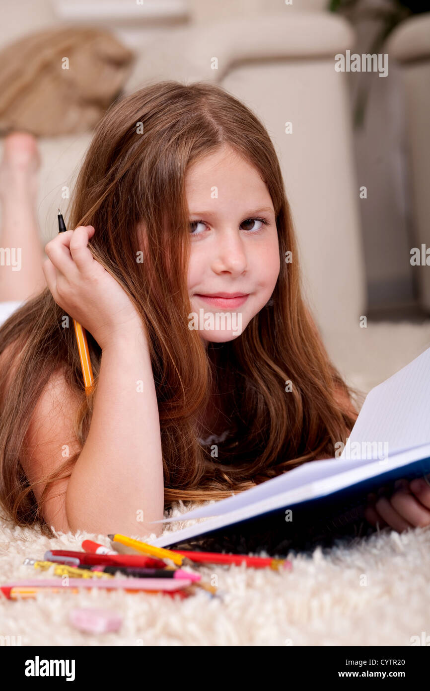 An attractive cute girl studying while lying on the floor and looking ...