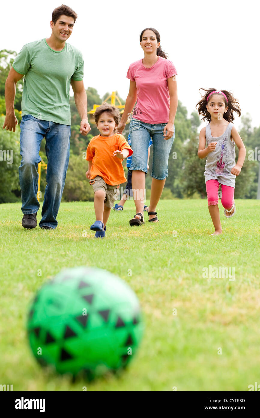 Kids run towards the football as parents follow them Stock Photo - Alamy
