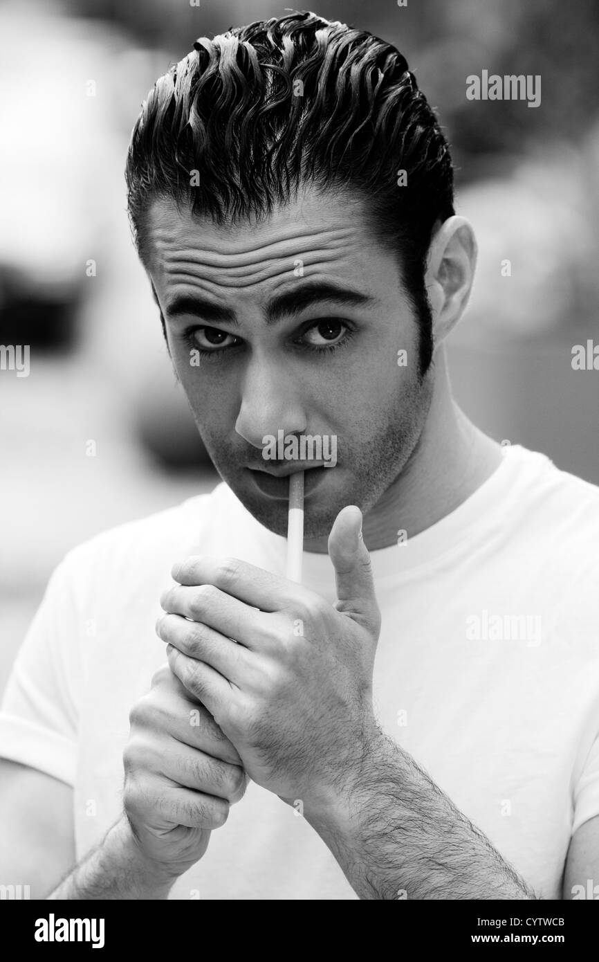 Handsome Caucasian man wearing white shirt lighting a filter cigarette ...
