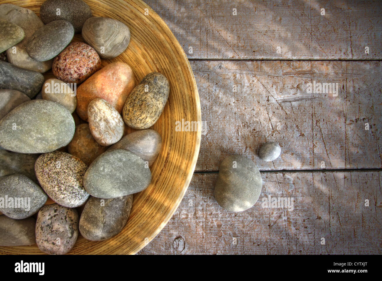 Spa rocks in wooden bowl on rustic wood table Stock Photo - Alamy