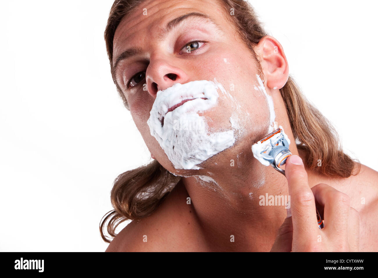 Portrait of a young handsome man shaving as part of his morning routine ...