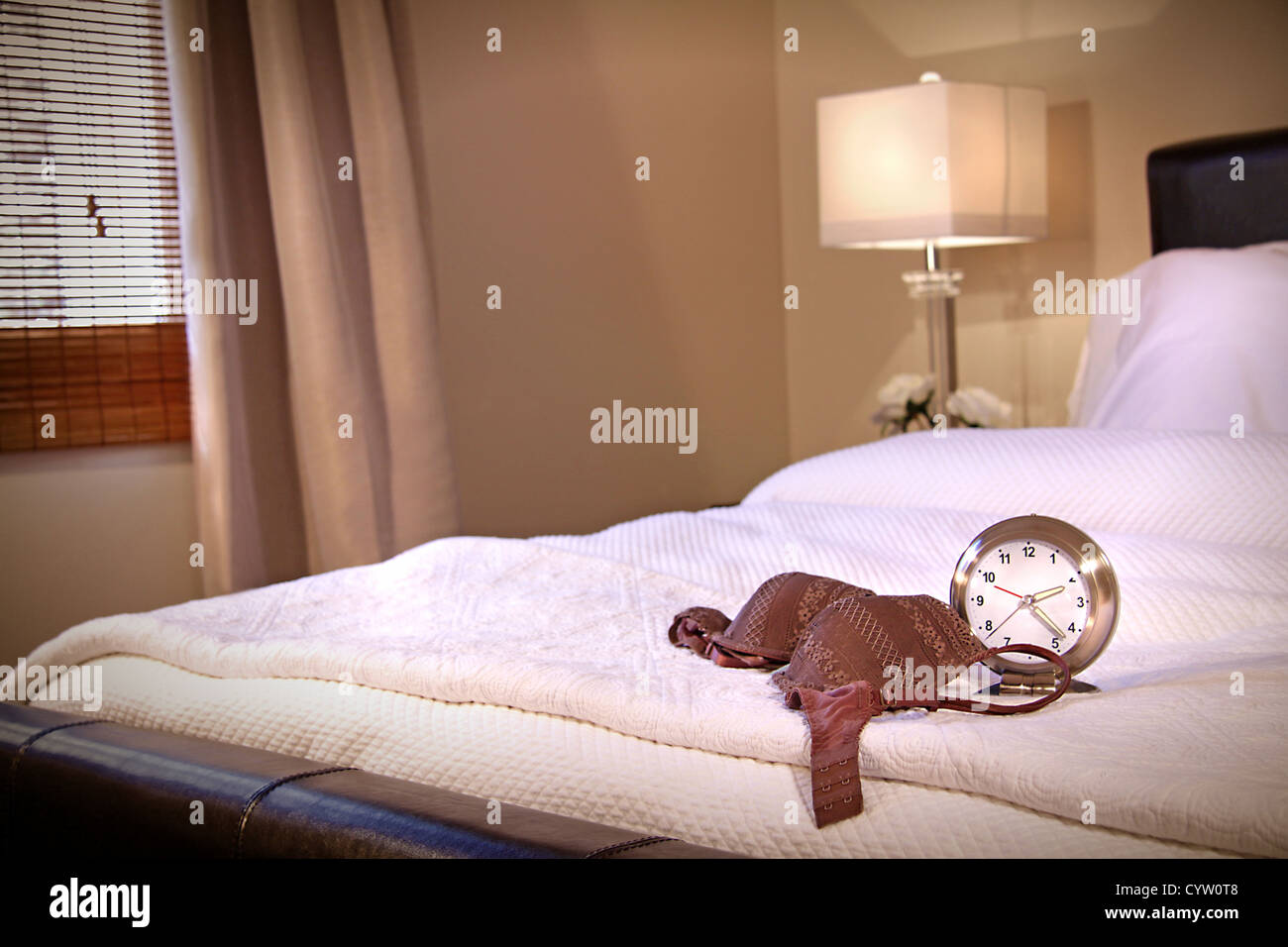 Lace brassierre laying across bed with clock Stock Photo - Alamy