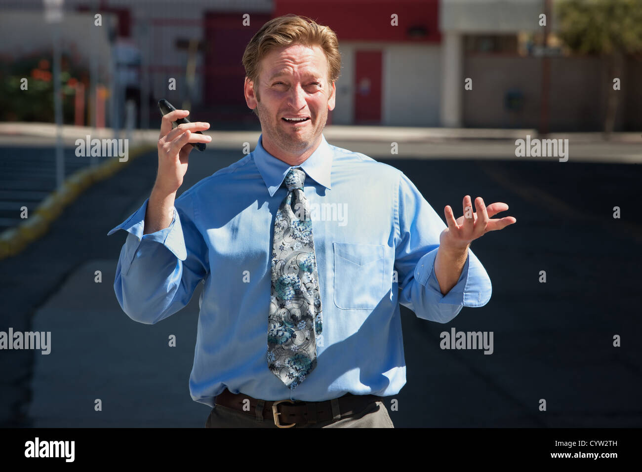 Exasperated business man with cell phone outdoors Stock Photo - Alamy