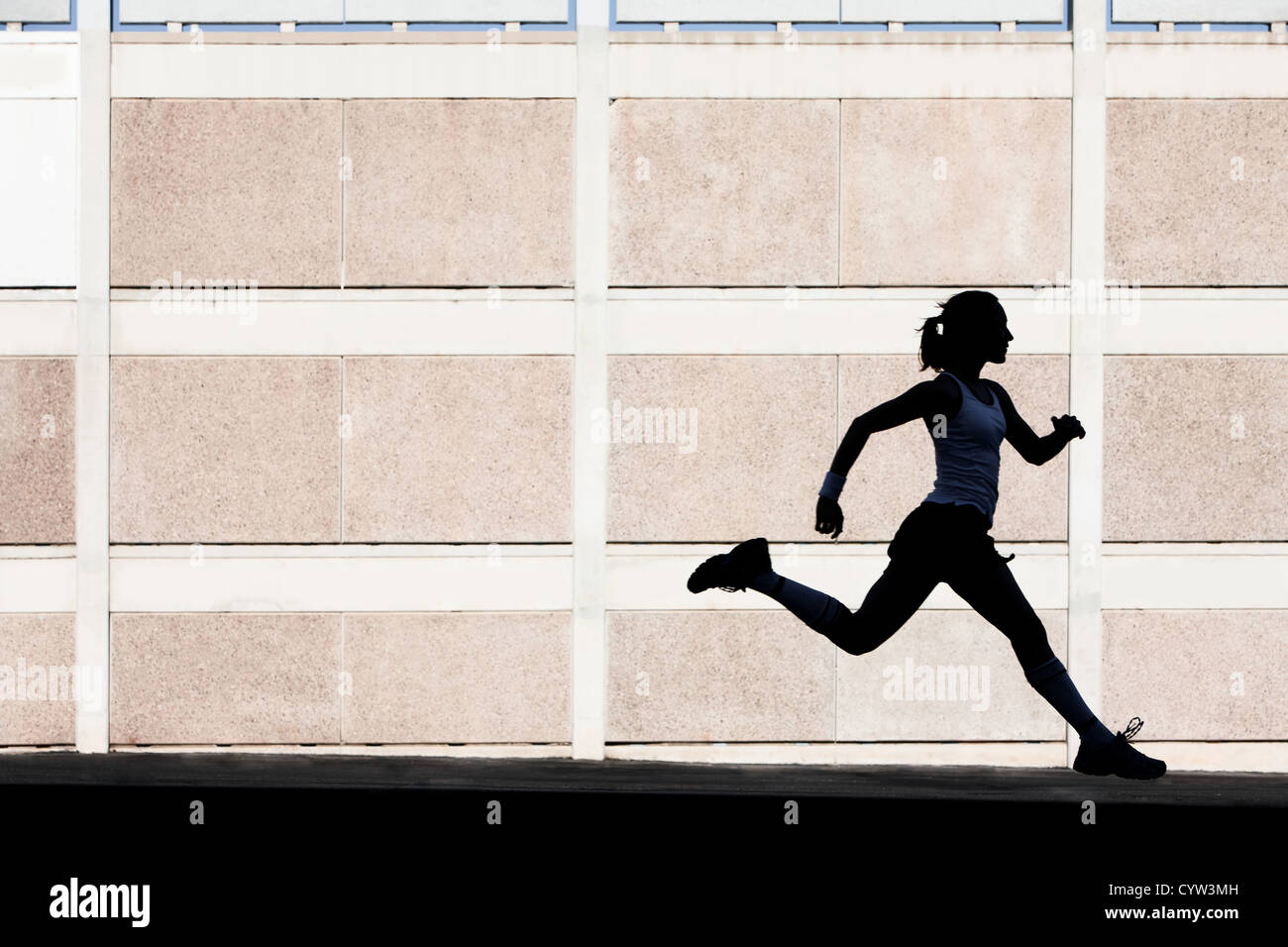 Woman in the shadows of building runs for exercise Stock Photo - Alamy