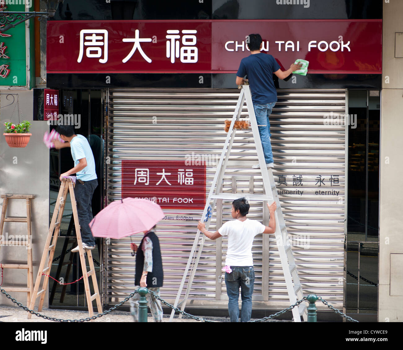 Men on a ladder cleaning a shopfront, Macau Stock Photo - Alamy