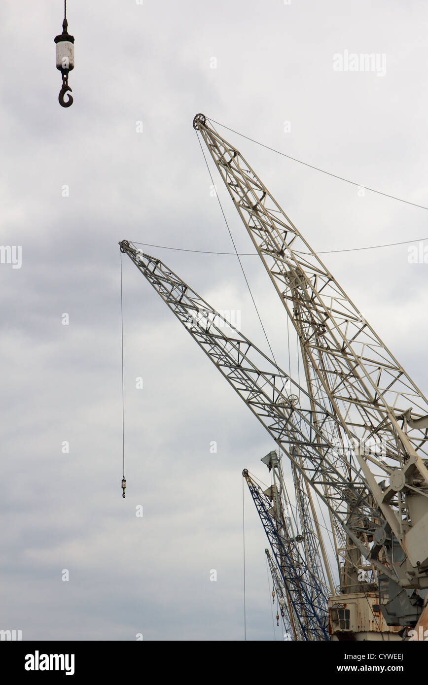 Rusty old harbor loading cranes sit abandoned against an overcast sky ...