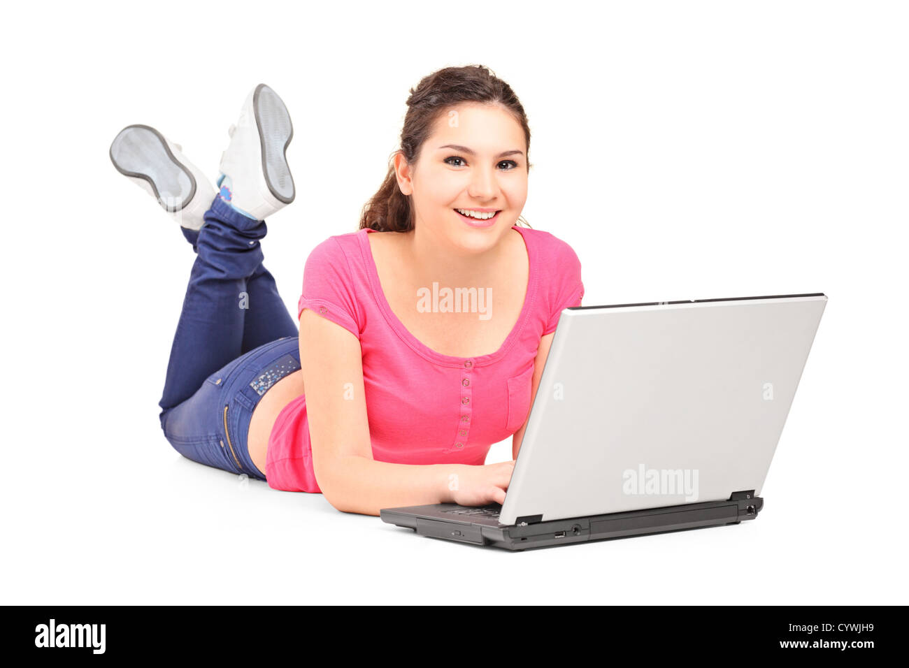 Smiling teenager doing her homework on a laptop isolated against white ...