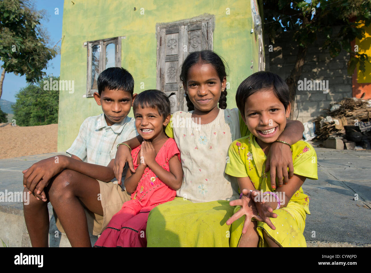 Happy young rural Indian village children sitting outside their home ...