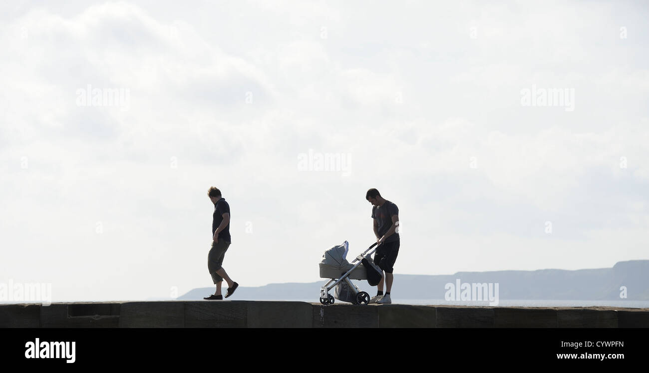 A man pushing a baby buggy along the sea wall scarborough england uk ...