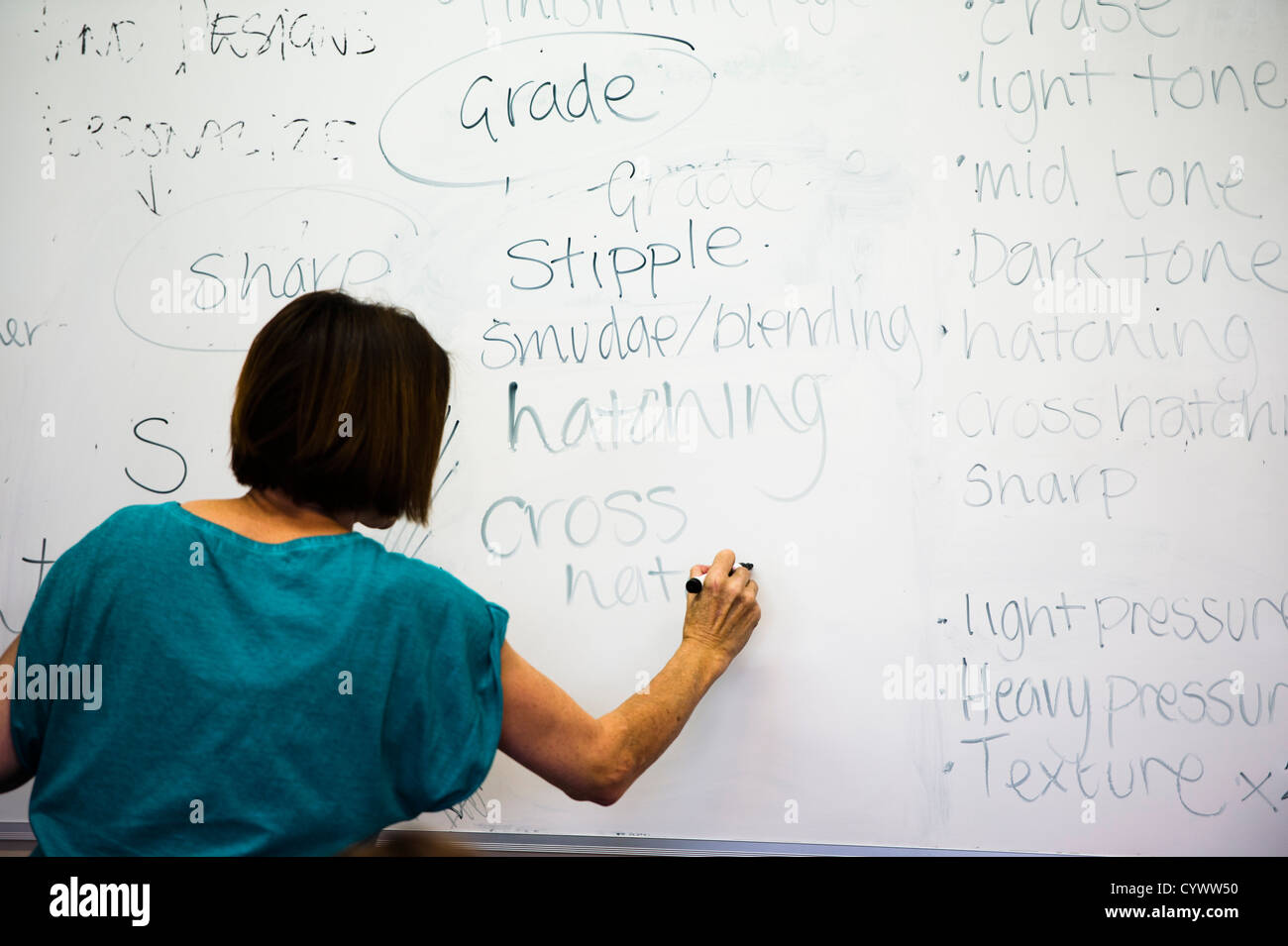A teacher writing art terms words on the board at a secondary school ...