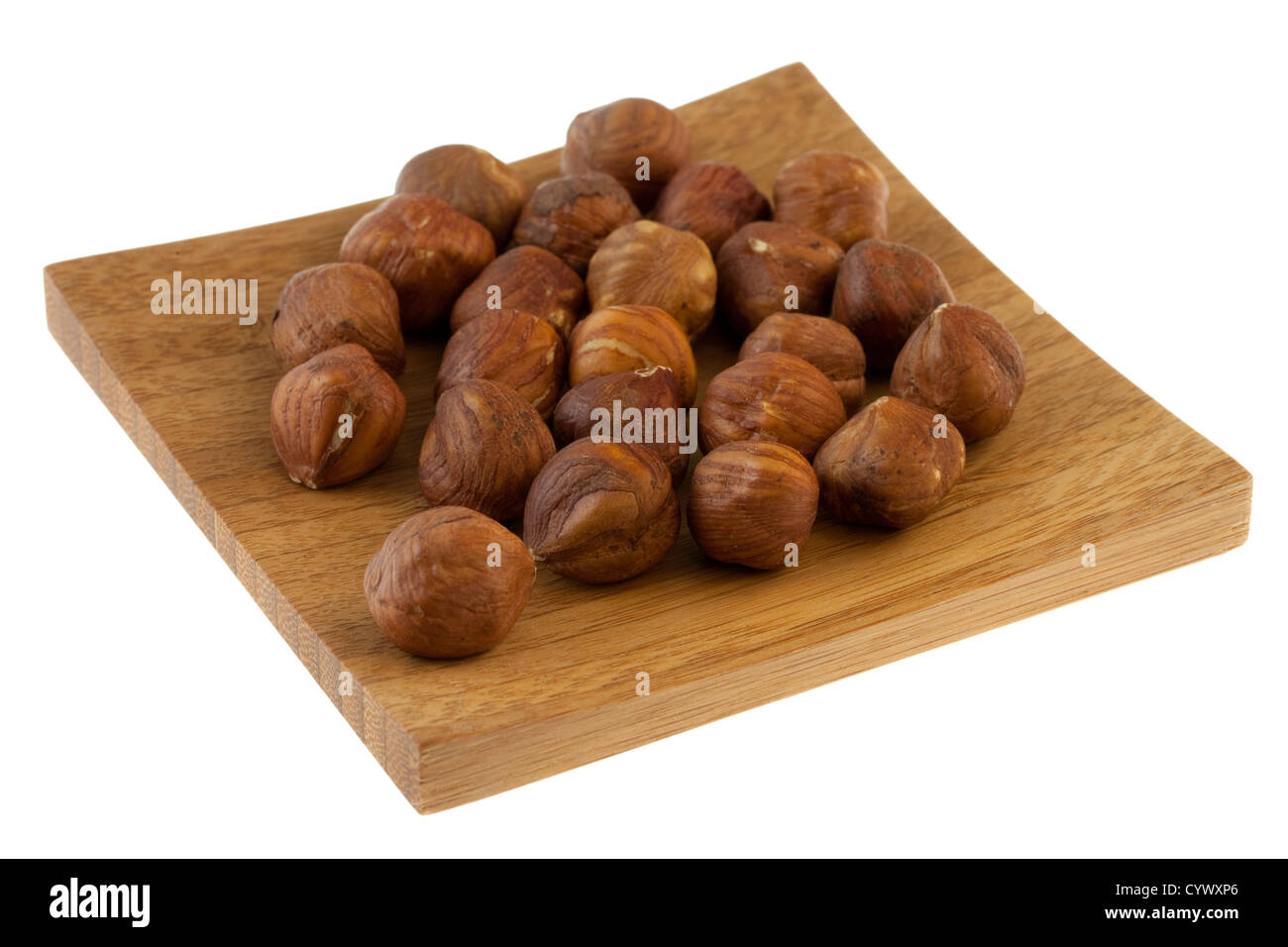 filberts (hazelnuts) on a small wooden square tray, isolated on white ...