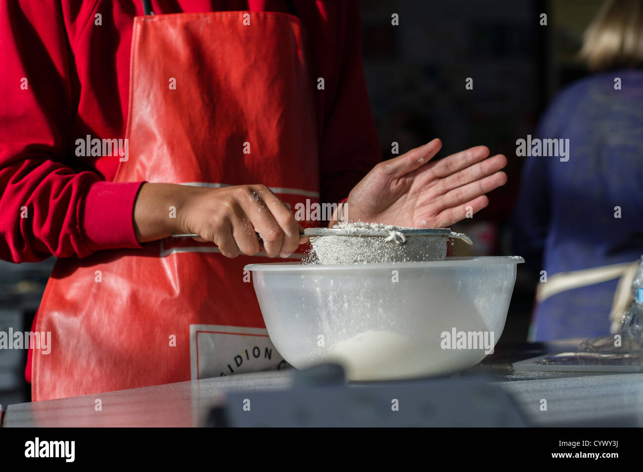 A girl sieving flour in a cookery food technology class in a secondary ...