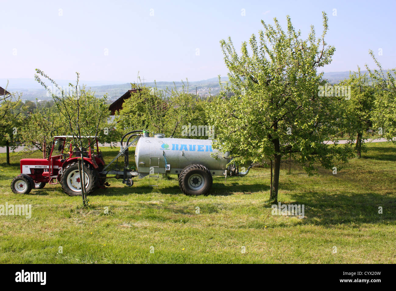 Red tractor in green field in Switzerland Stock Photo - Alamy