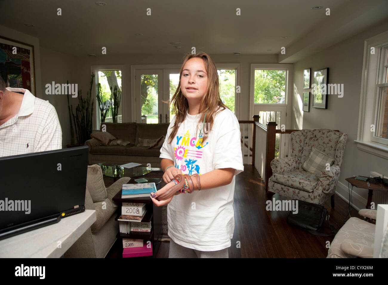 Teenage girl at home with pet snake wrapped around wrist, reptile ...
