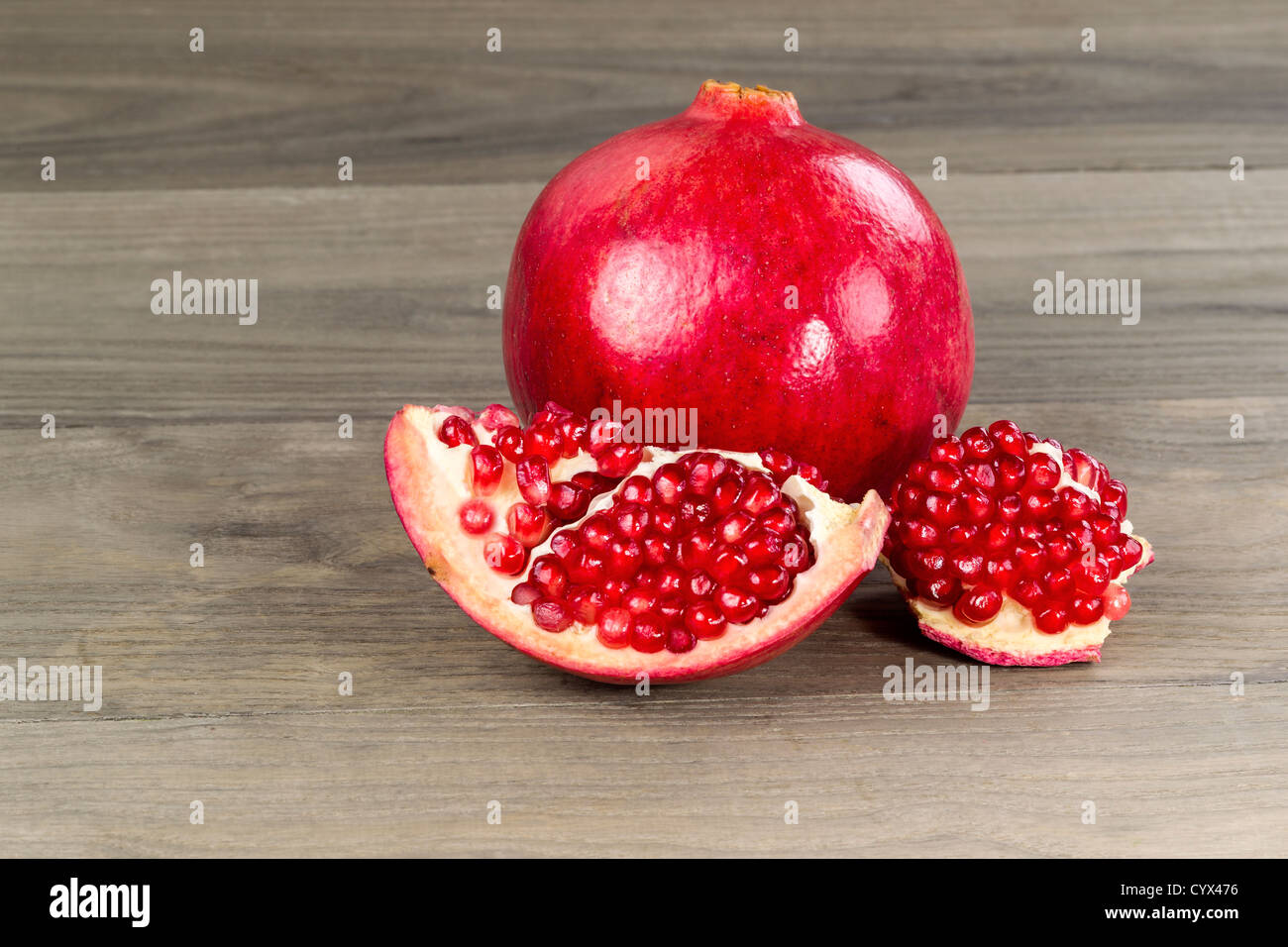 Open Pomegranate fruit with whole piece and faded wood in background ...