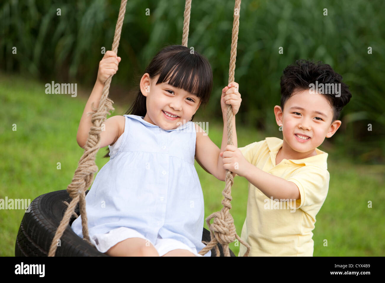Happy children playing on a swing Stock Photo - Alamy