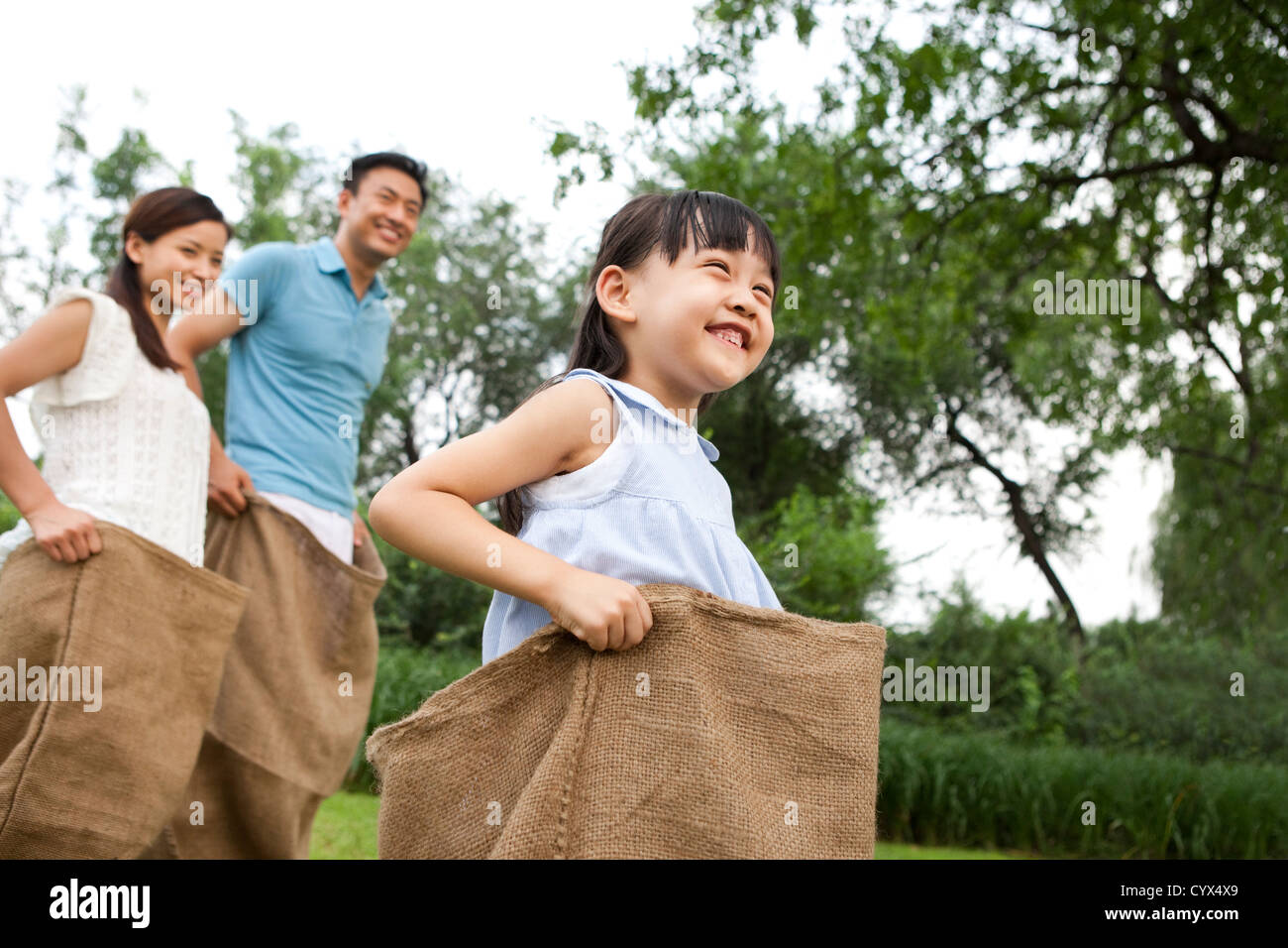 Cheerful family playing sack race Stock Photo - Alamy