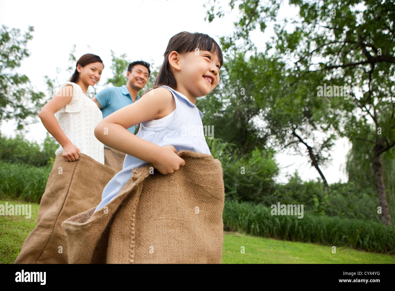 Cheerful family playing sack race Stock Photo - Alamy