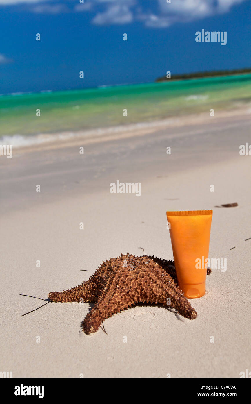 Red starfish and sunscreen tube on a beautiful tropical beach, beauty ...