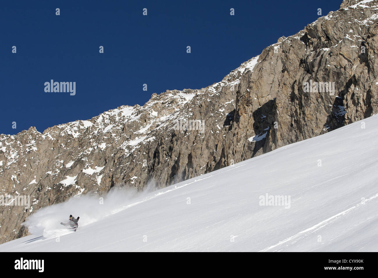 a female snowboarder throws up powder fresh snow while making a turn ...
