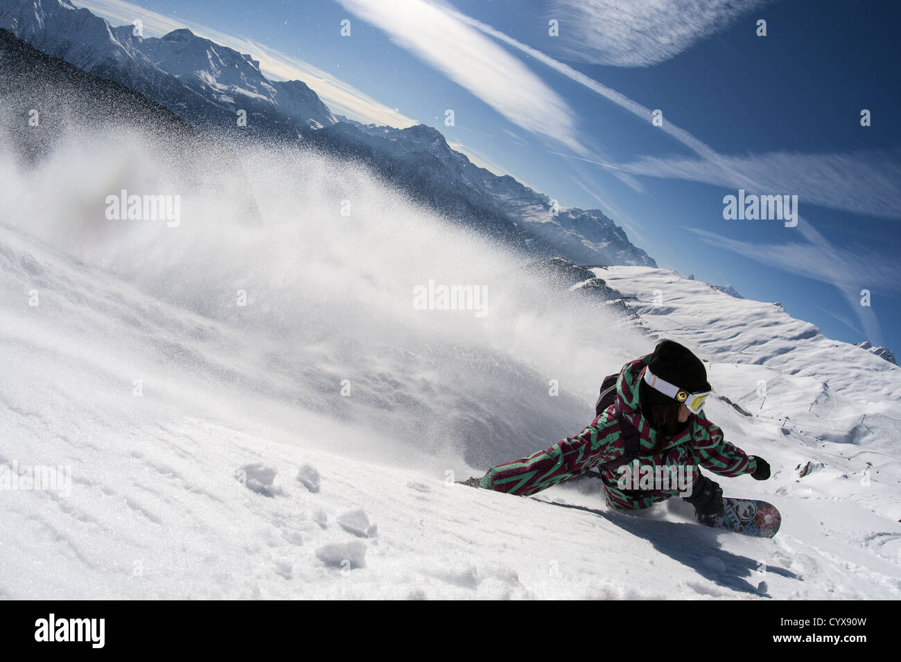 a female snowboarder passes by throwing up snow Stock Photo - Alamy