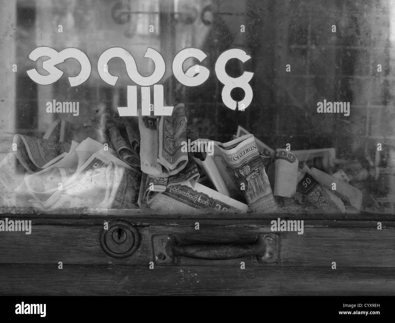 a glass fronted box contains offerings of money in a Burmese temple ...