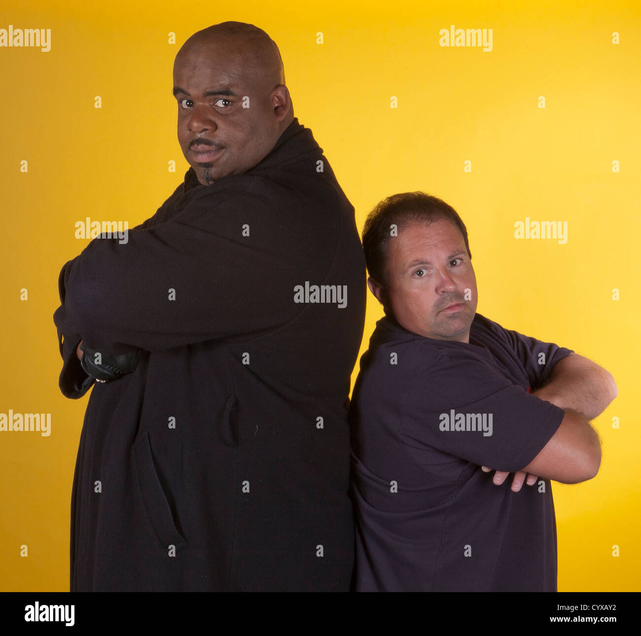 Bouncers standing back to back glaring Stock Photo - Alamy
